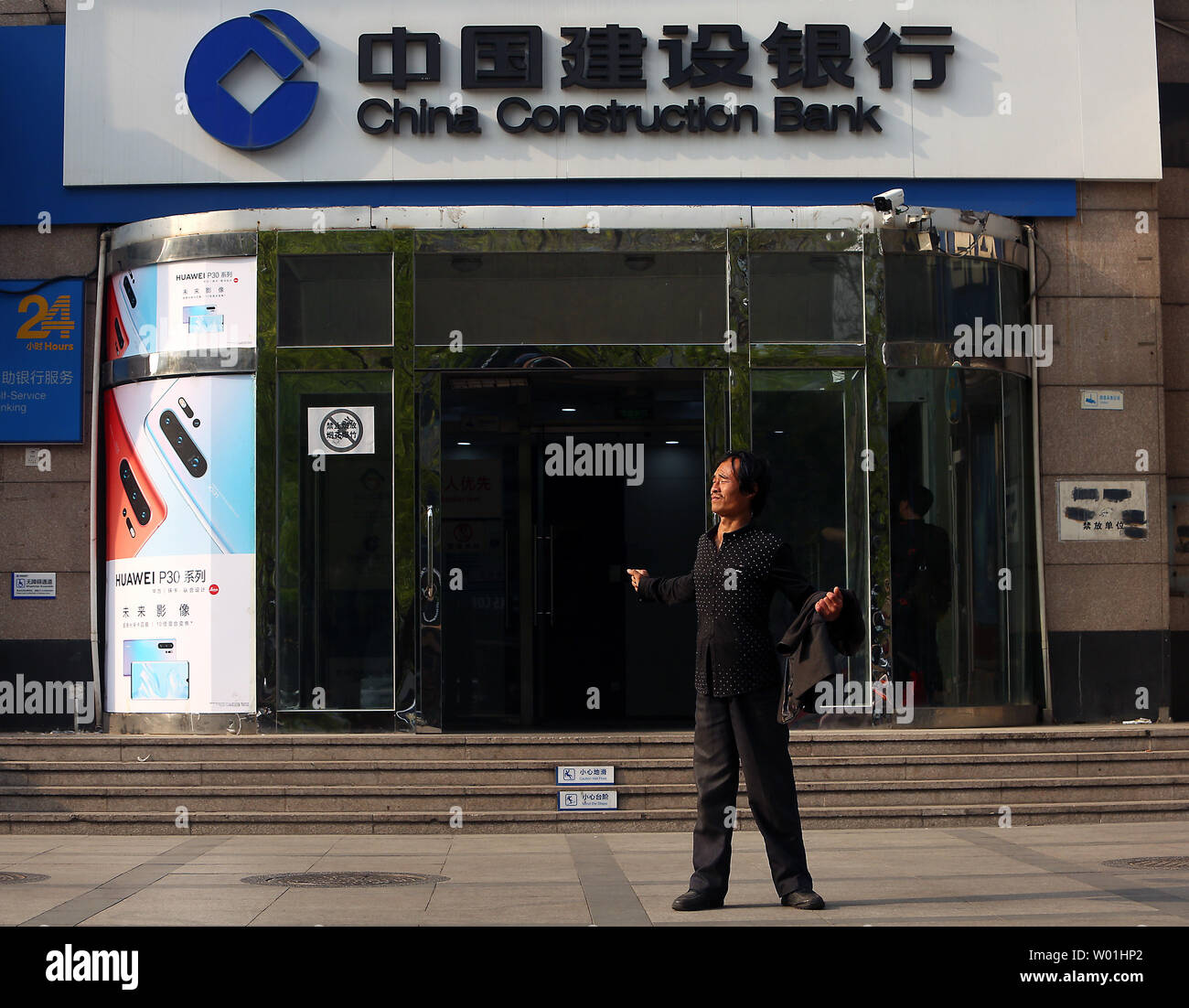 Chinese walk by a China Construction Bank branch in Beijing on April 18 ...