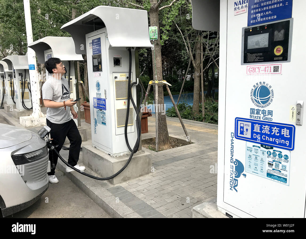 A Chinese driver prepares to charge his electric car at a new charging ...