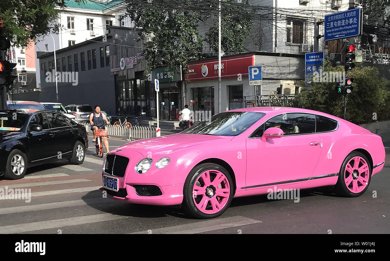 A bright pink Bentley crosses an intersection in downtown Beijing on ...