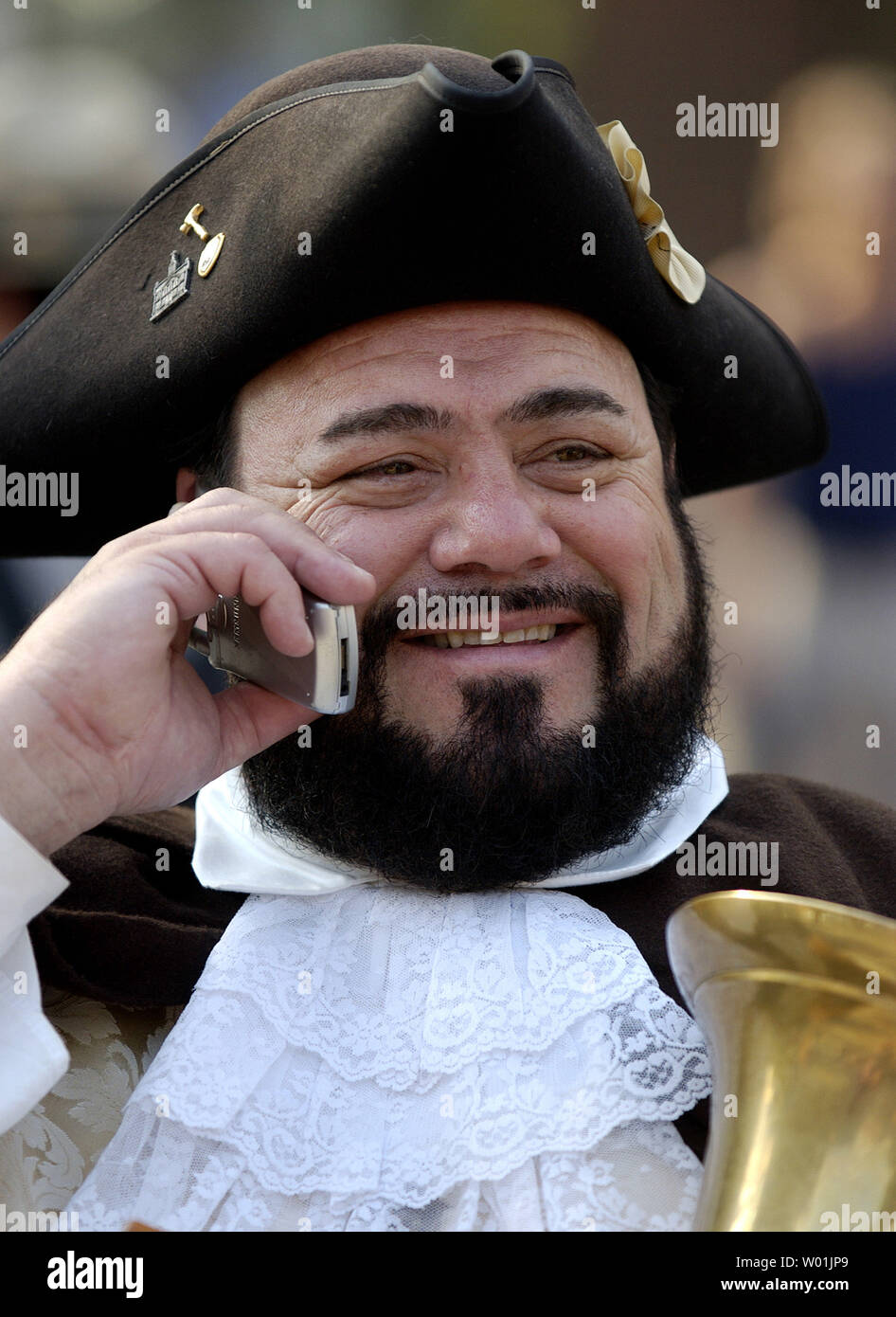 Town Cryer, actor Richard Lalena, pauses with his bell to use his cell ...