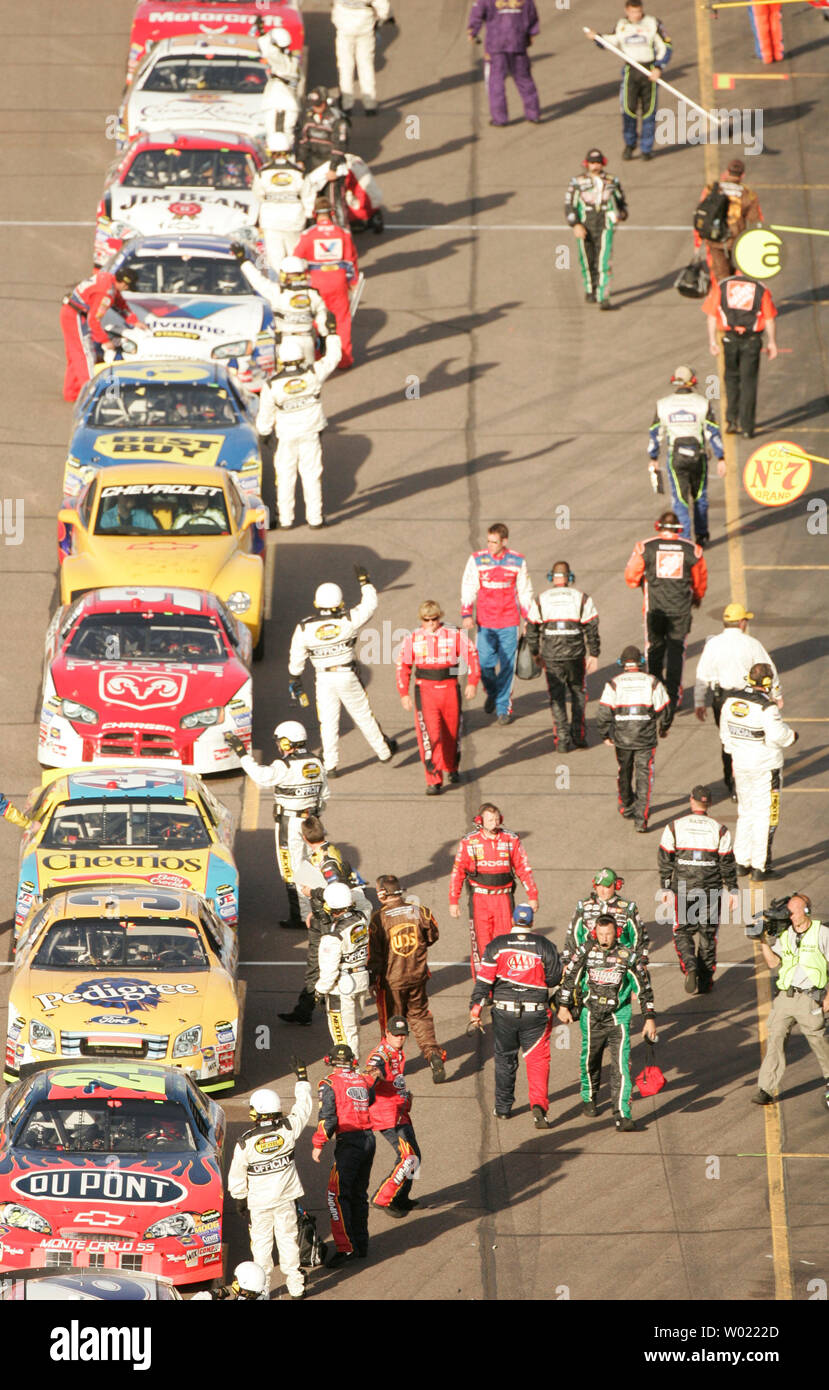 NASCAR officials (in white suites and helmets) signal that the car they ...