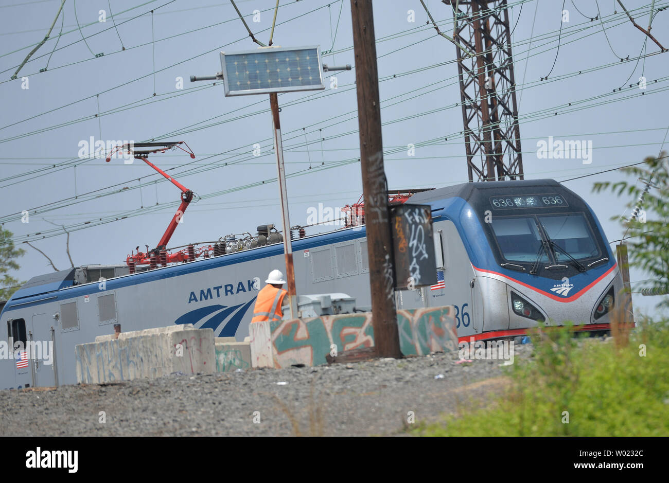 An Amtrak Acela train slowly passes a police car as it travels near the ...