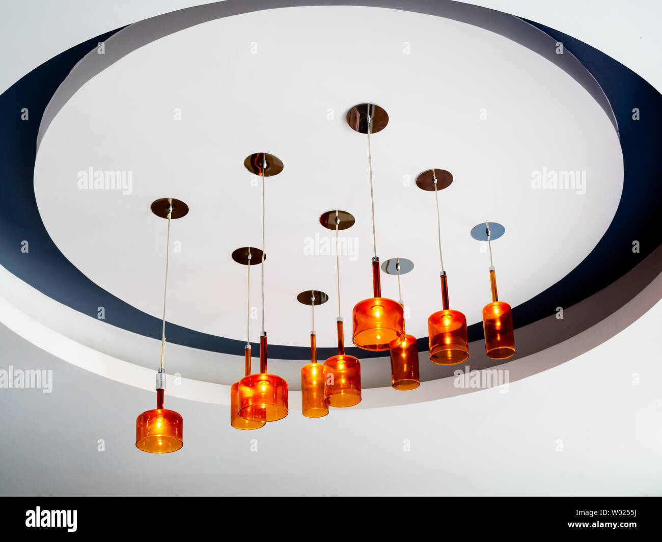 Modern orange ceiling lamp hanging from round white ceiling. Lighting ...
