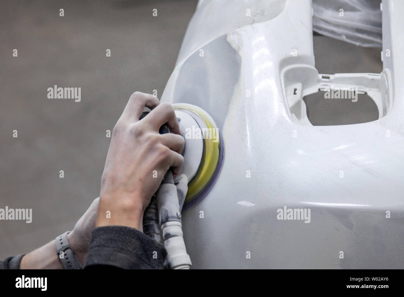 Preparation for painting a car element using sander and putty by a ...