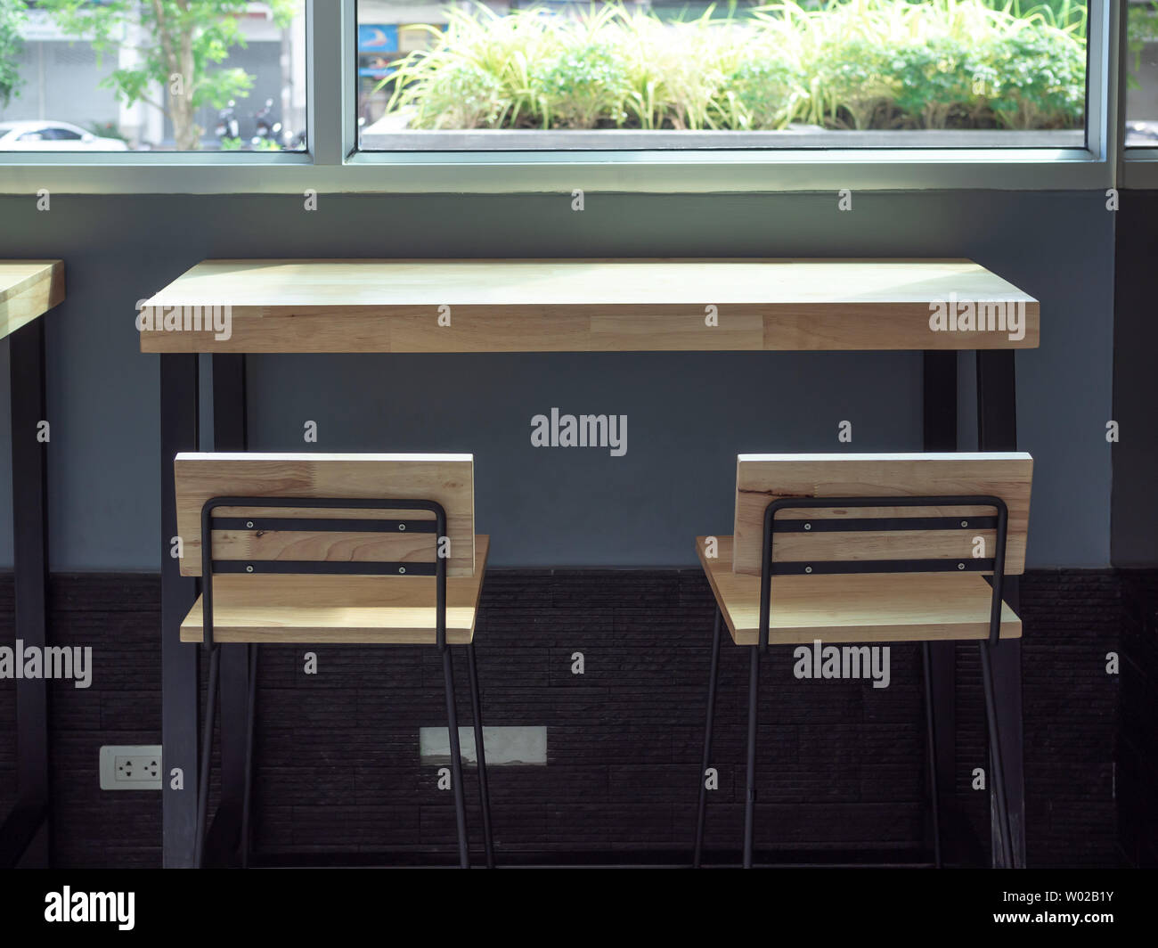 Wooden bar stools and wooden table near the window glass with morning ...