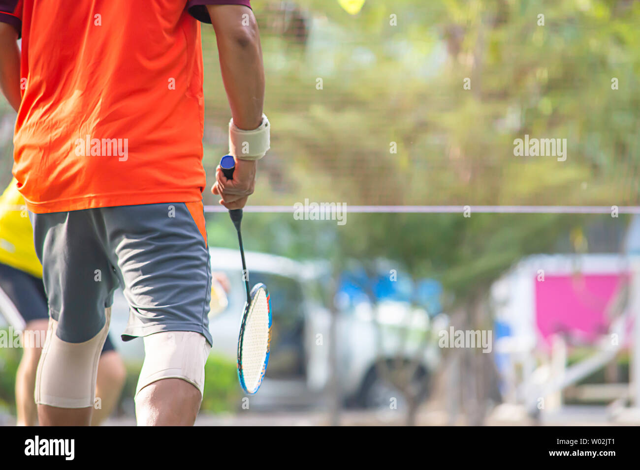 Elderly man Hand holding a badminton racket Background blur tree in ...