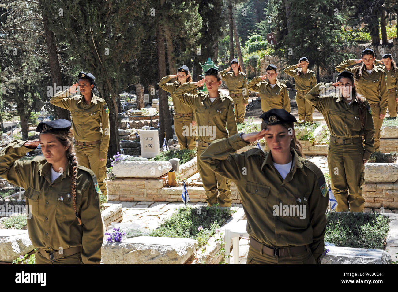 Israeli soldiers salute after placing small national flags and flowers ...