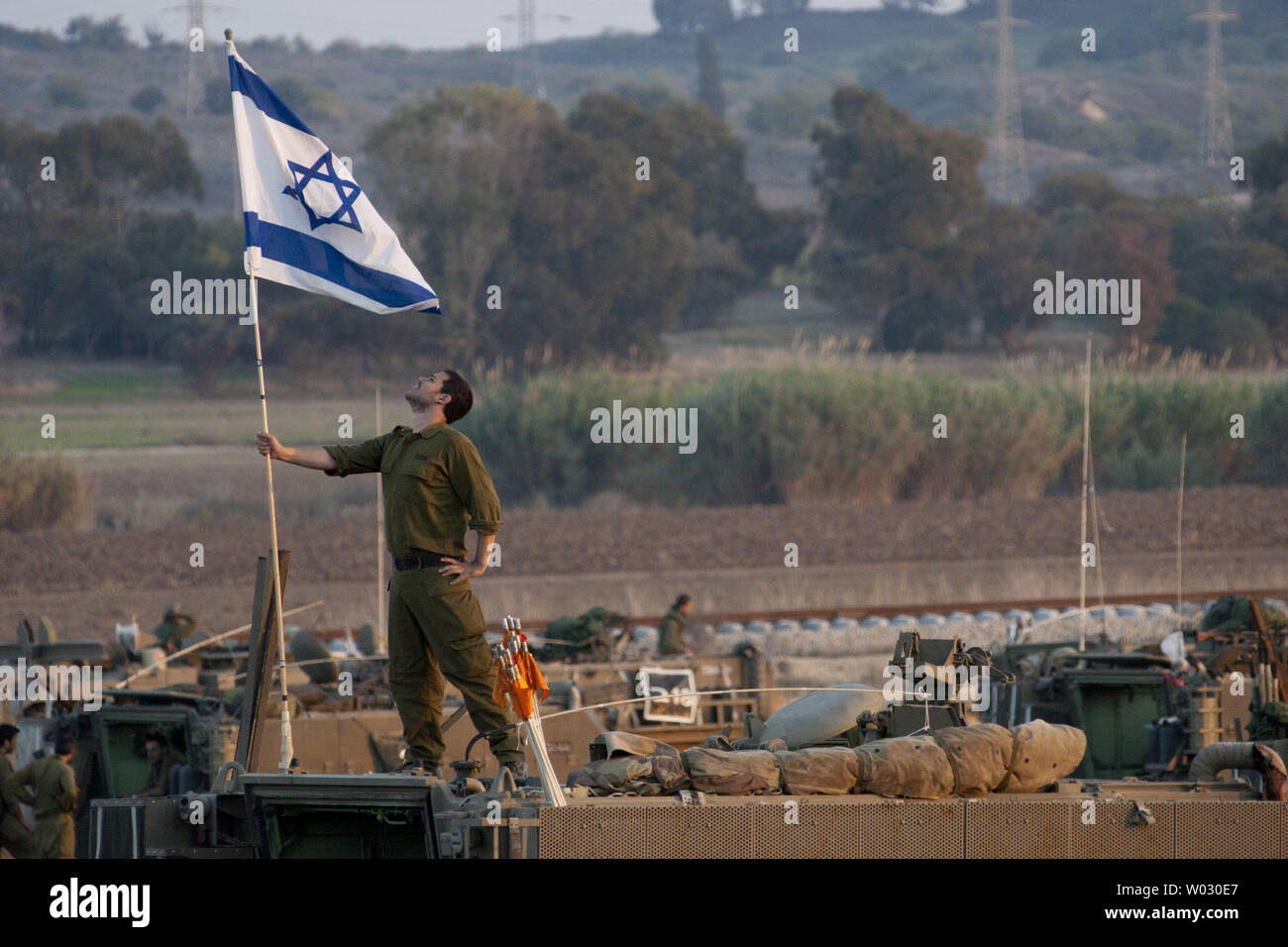 An Israeli raises his national flag on an APC as Israeli army units ...
