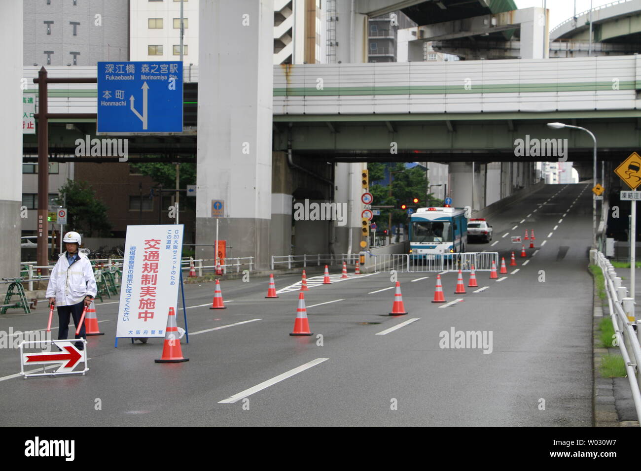 A police officer controls traffic on a street in central Osaka, western ...