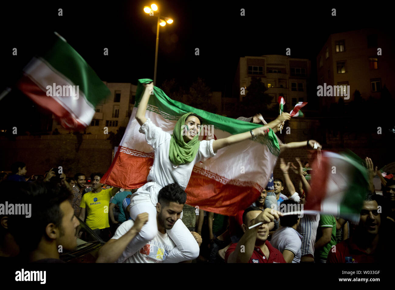 An Iranian soccer fan holds the Iranian flag as she dances on streets ...
