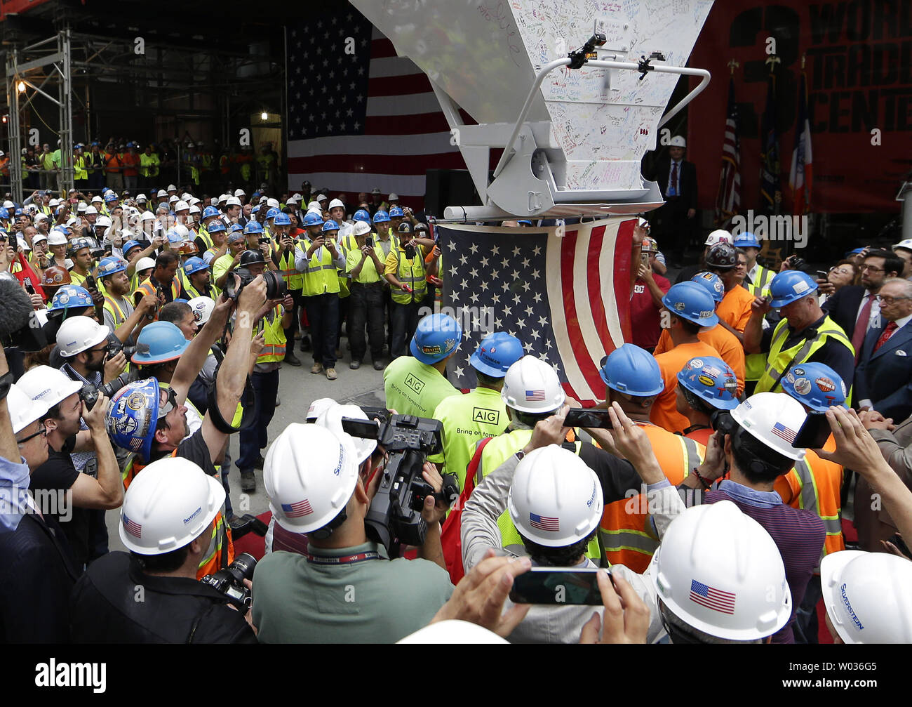 Construction workers watch the last concrete bucket with an American ...