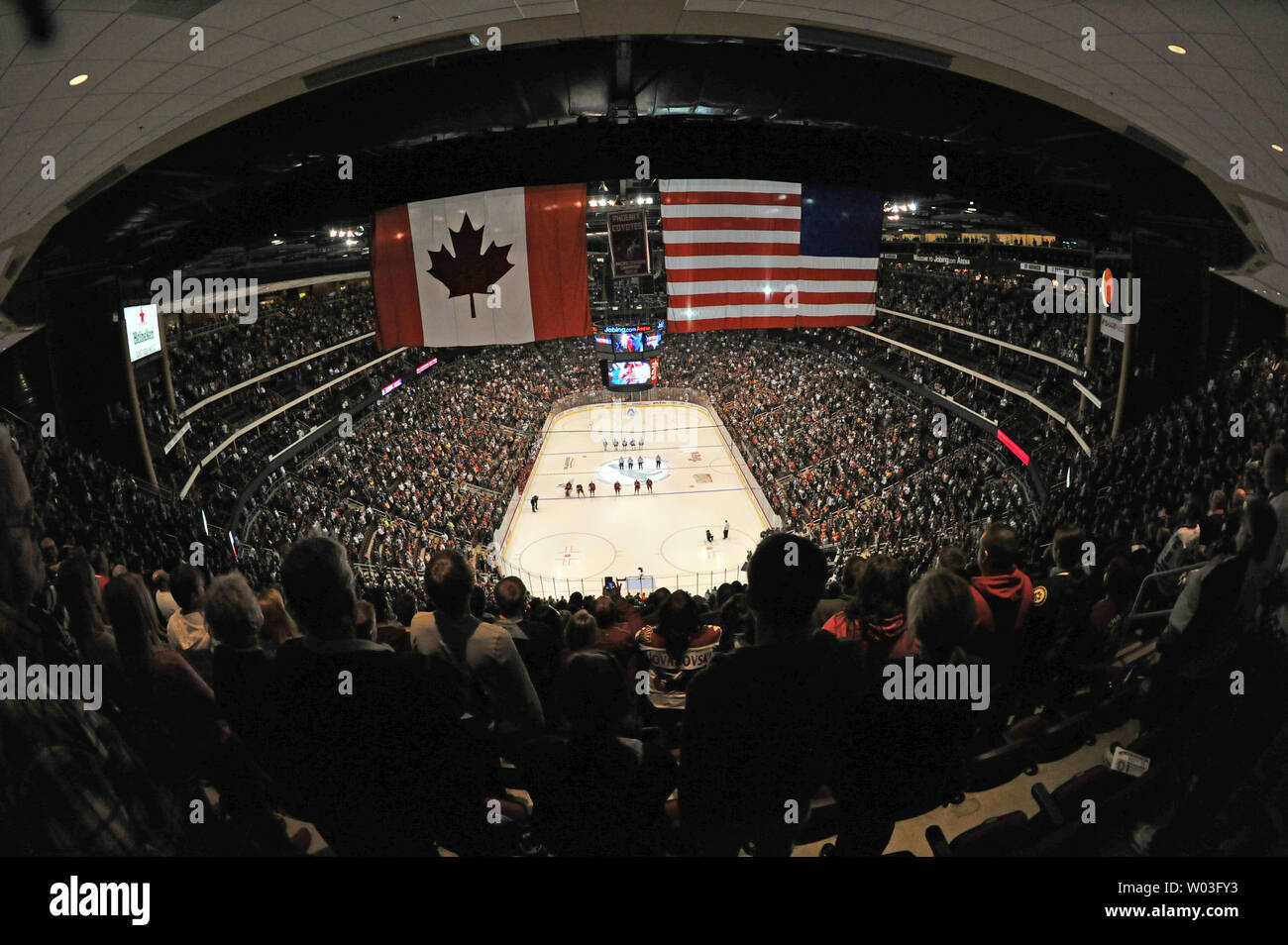 Chicago Blackhawks and Phoenix Coyotes players stand on the ice for the ...