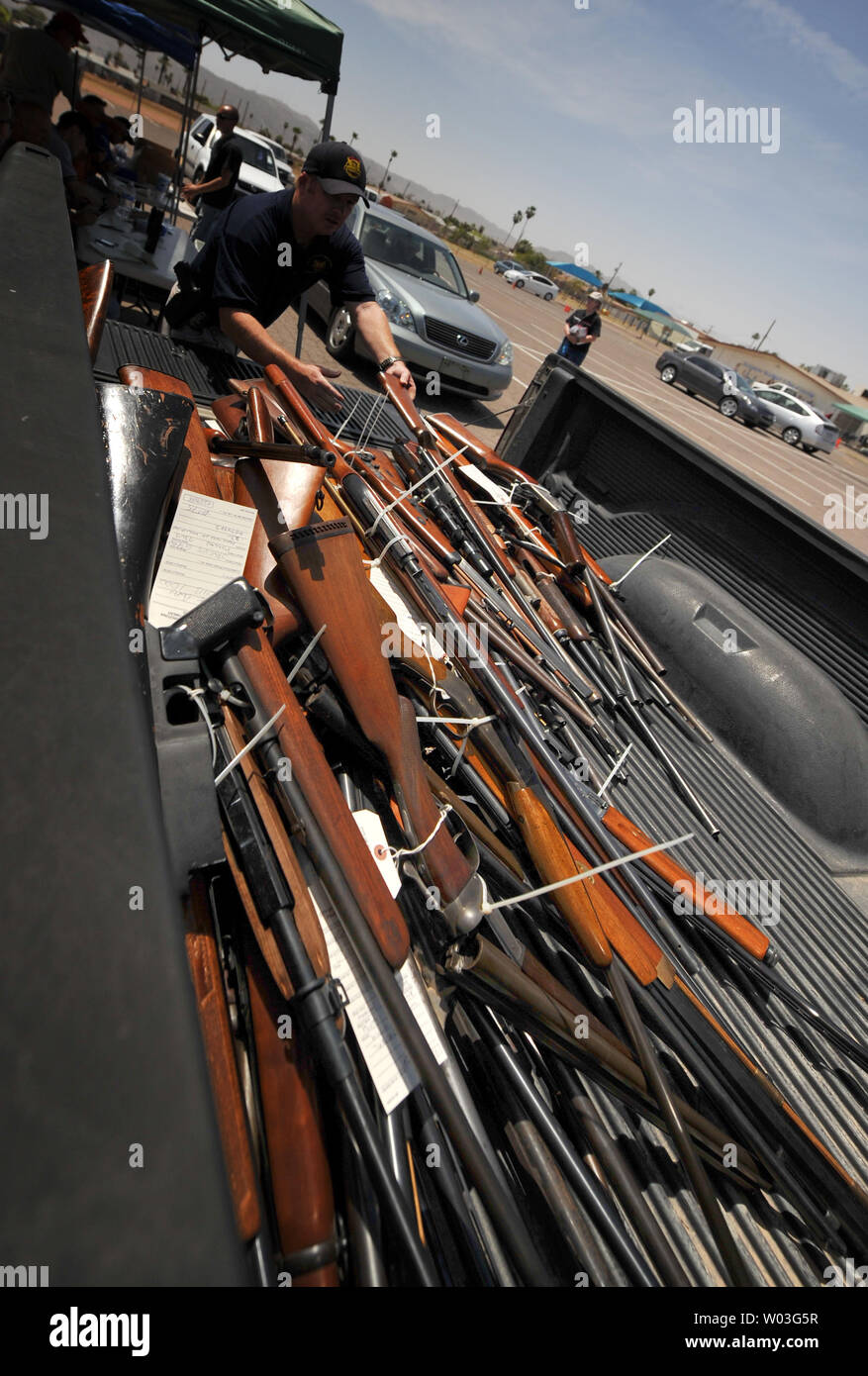 A Phoenix Police officer puts a rifle in the back of a pickup truck at ...
