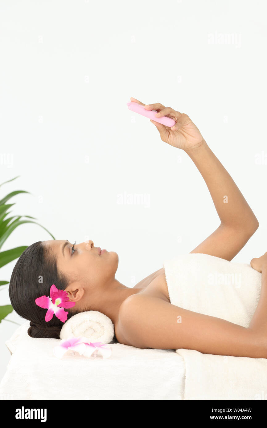 Woman relaxing on a massage table and text messaging Stock Photo - Alamy