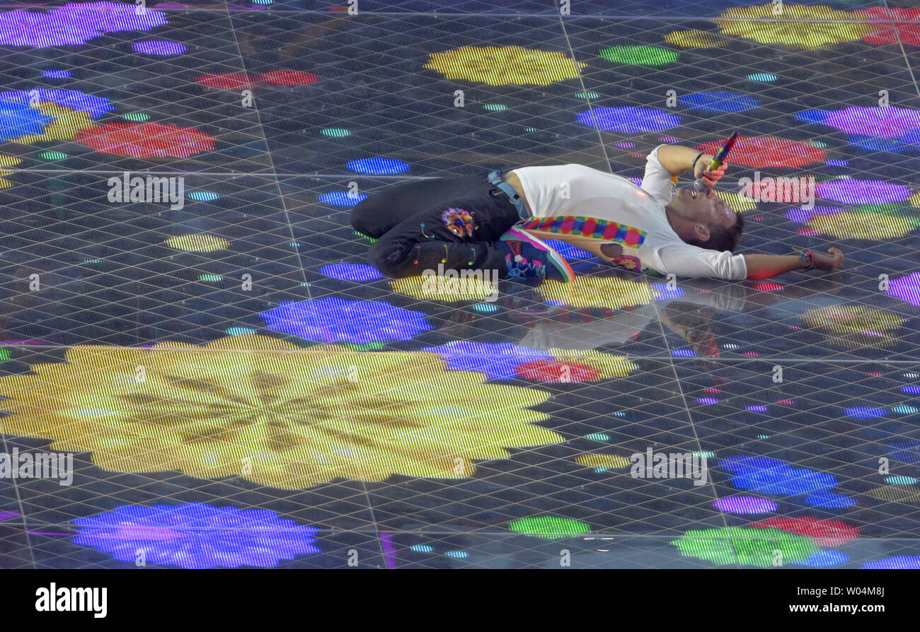 Coldplay front man Chris Martin sings on his back during the Super Bowl ...