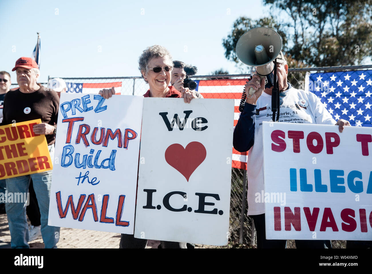 Demonstrators hold signs at an "America First" rally at the San Ysidro ...