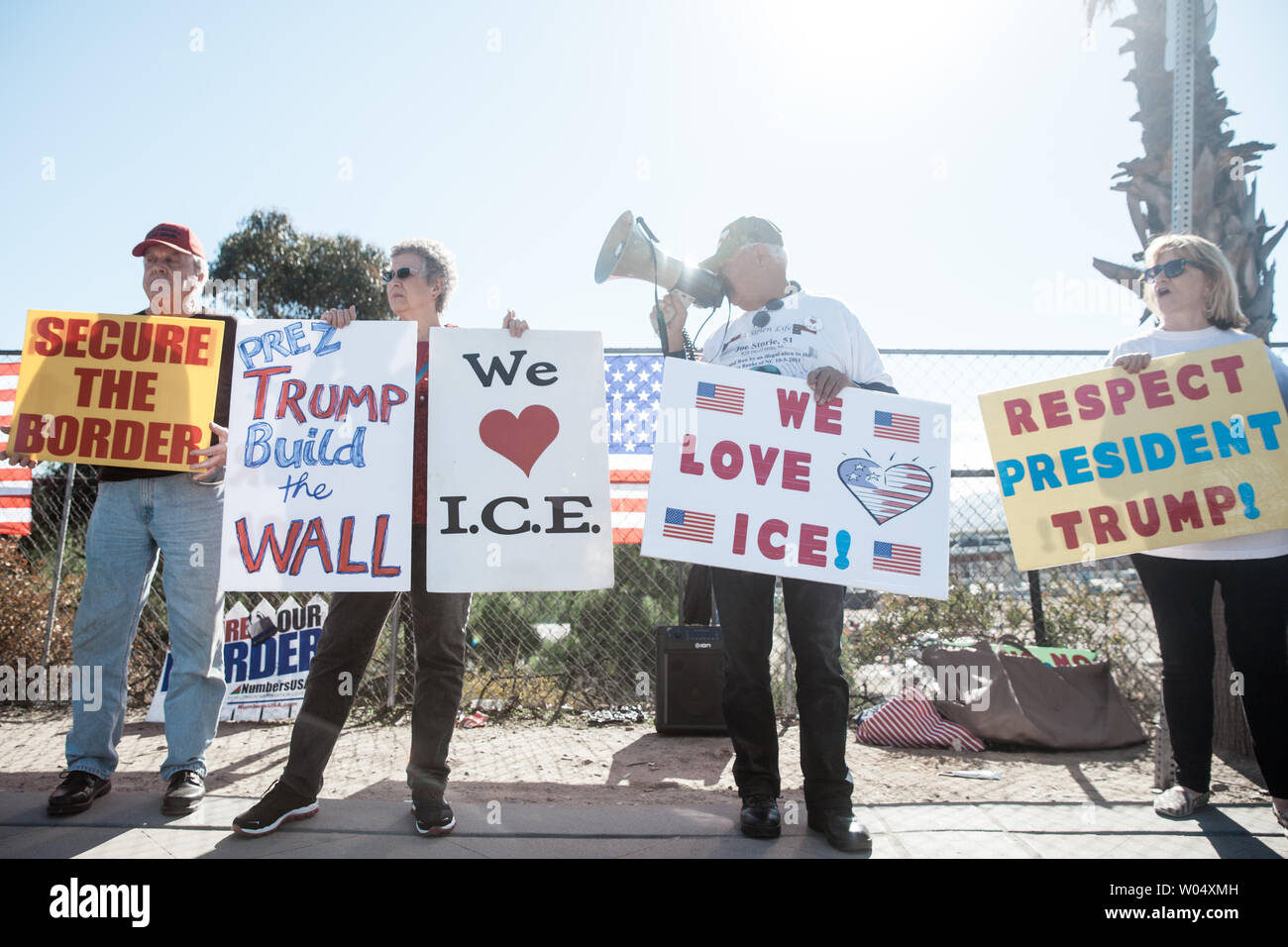Demonstrators hold signs at an "America First" rally at the San Ysidro ...