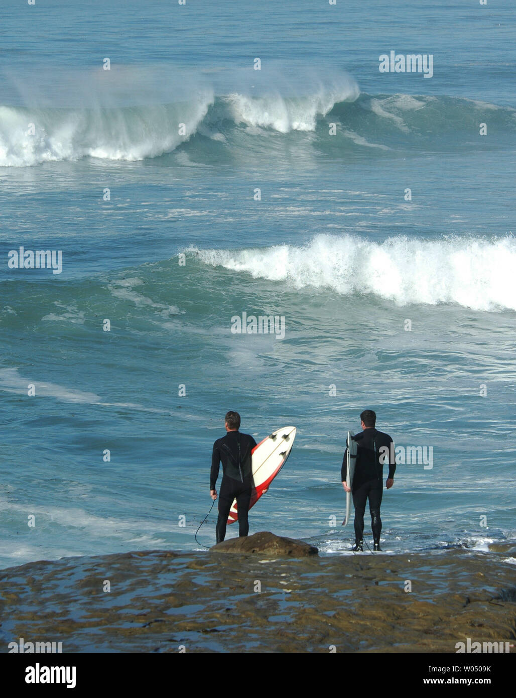 Two surfers check out the large waves at Ocean Beach, California ...