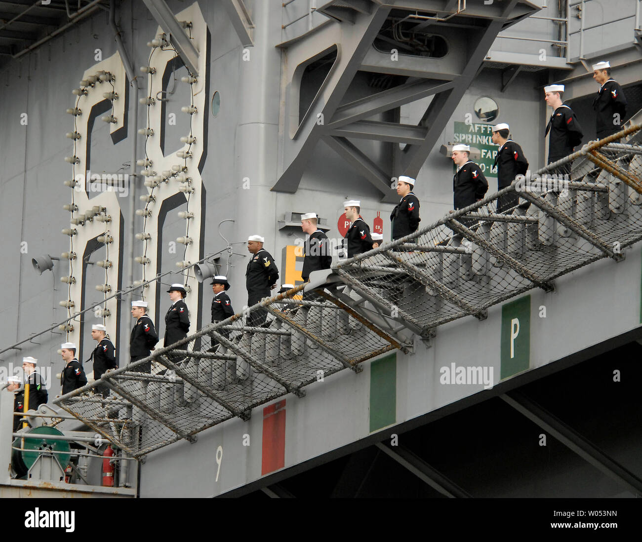 Crew members of the aircraft carrier USS Nimitz line the deck as the ...