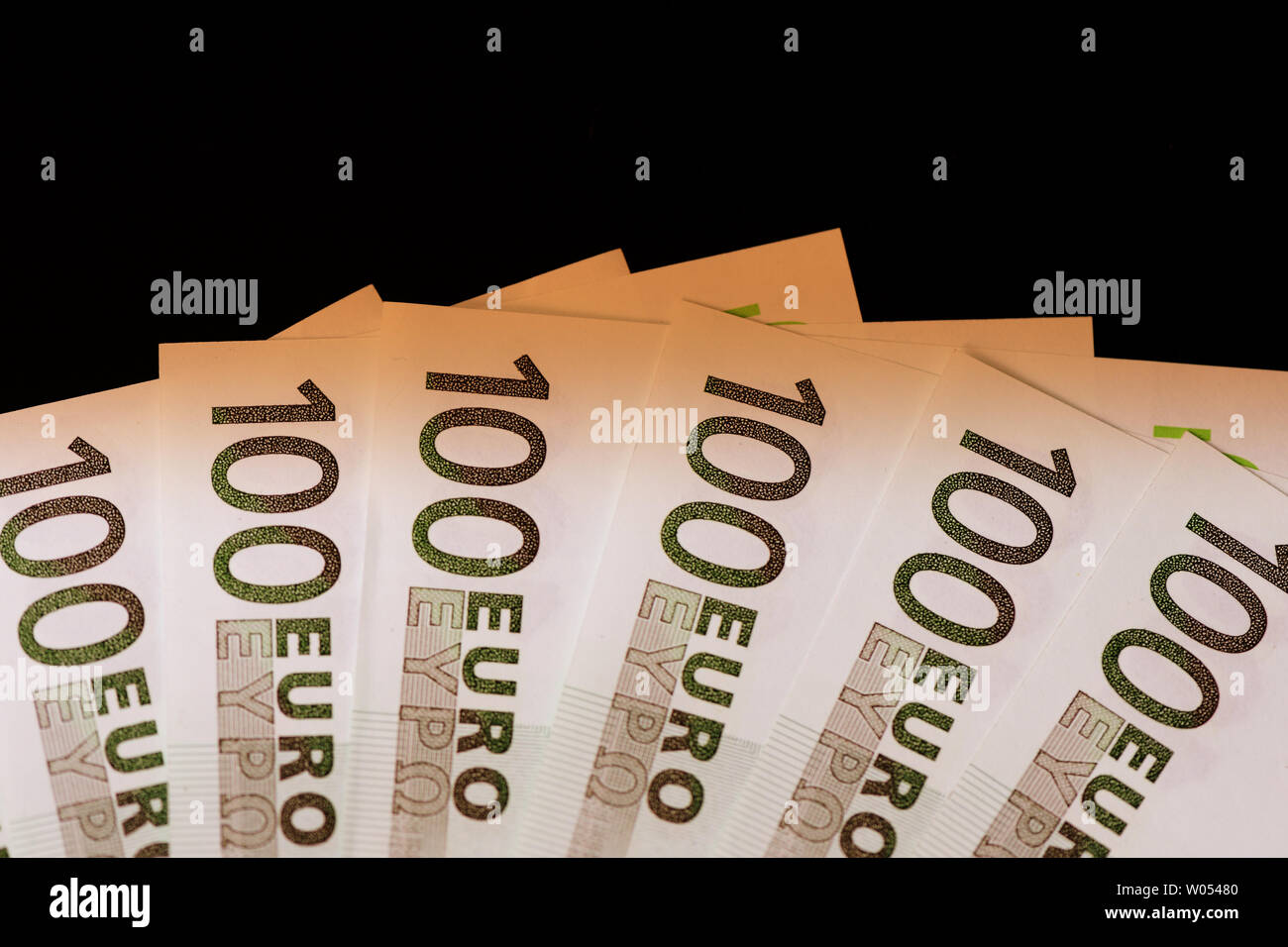 One hundred euro notes on a dark background close up. Brown color toned ...