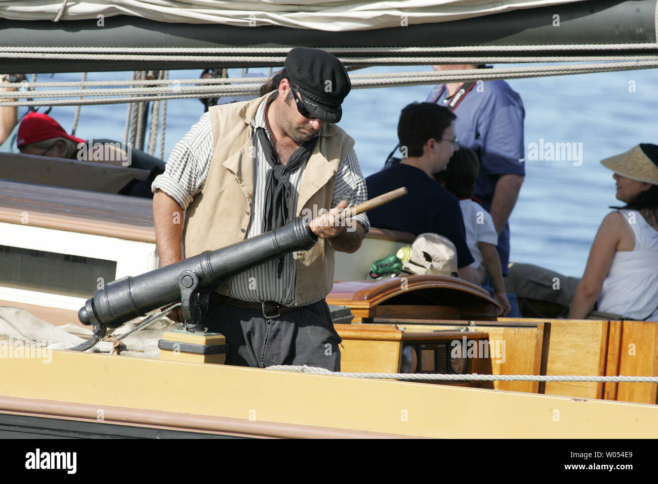 A gunners mate dressed in 1812 costume loads a cannon on the deck of ...