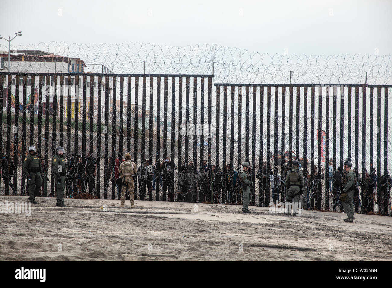 Border Patrol agents stand in front of the border fence that divides ...