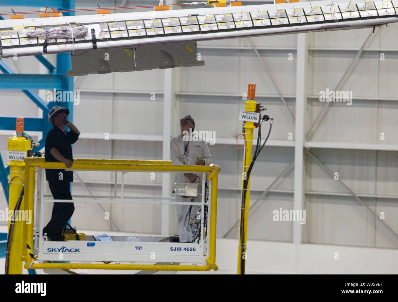 Workers inspect the underside wing of a Boeing 787 airplane as it sits ...