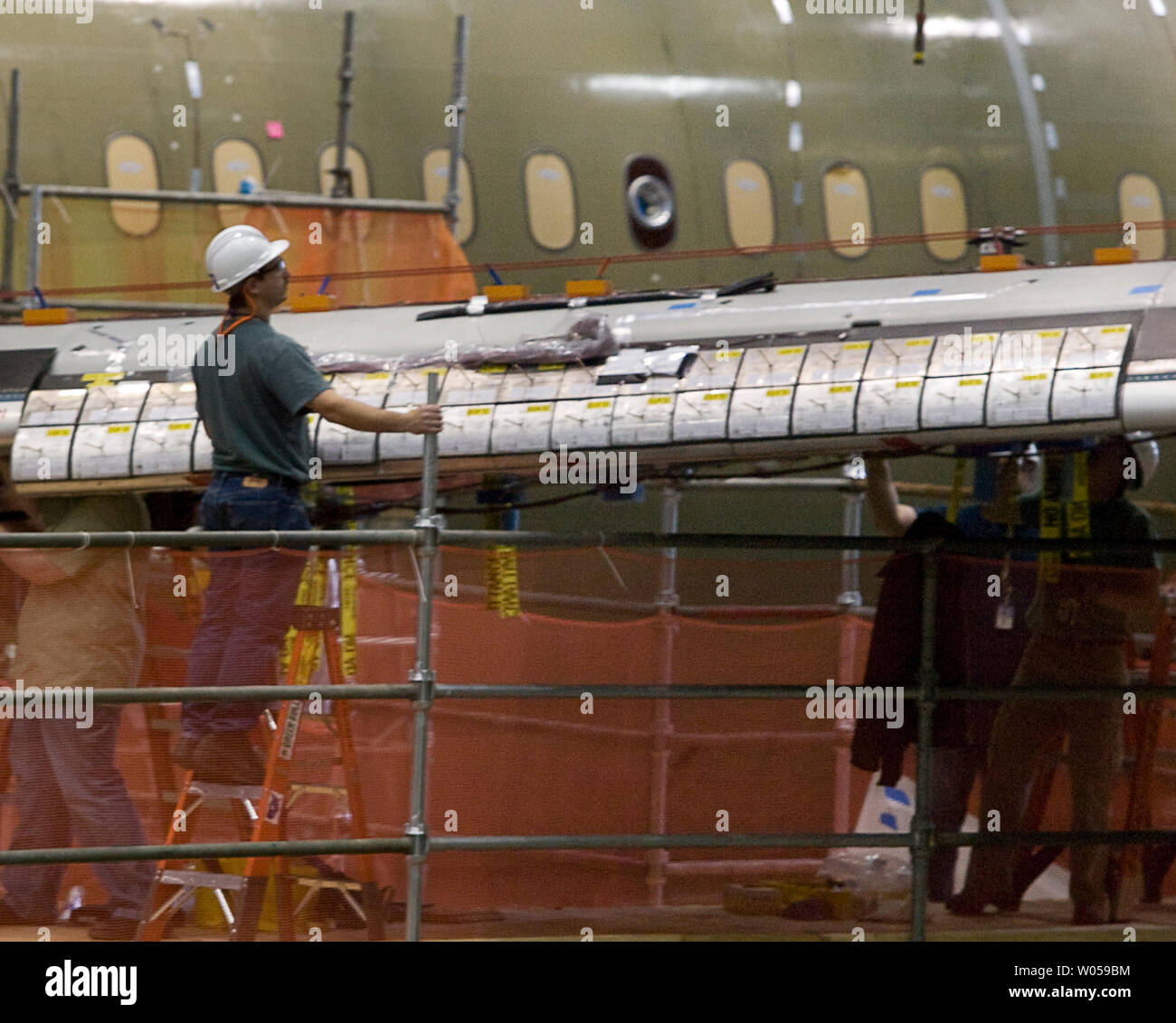 Workers inspect the the wing of a Boeing 787 airplane as it sits in a ...
