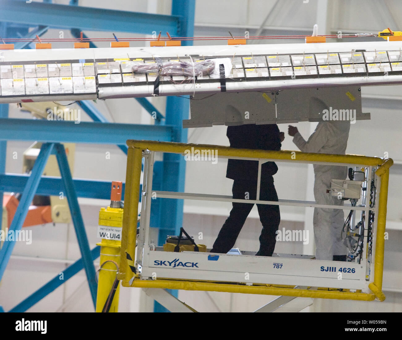 Workers inspect the underside wing of a Boeing 787 airplane as it sits ...