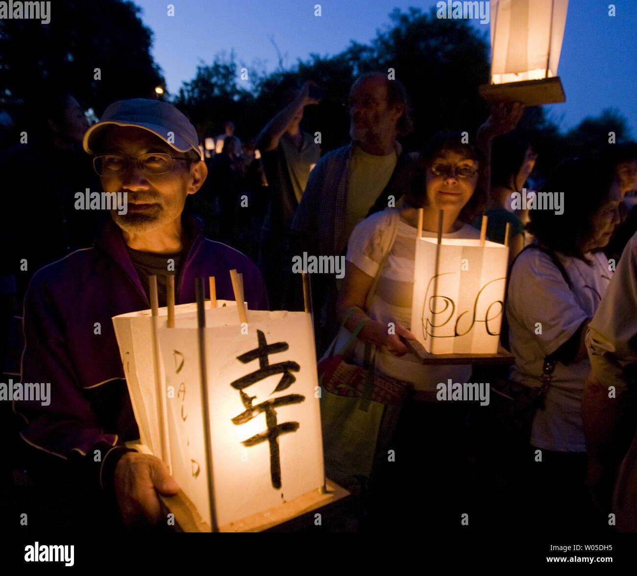 Stan Shikuma carries to lighted lanterns as to float in Green Lake ...