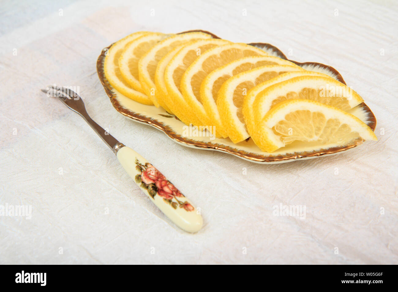 Mellow lemon slices on a plate with fork on white tablecloth Stock ...