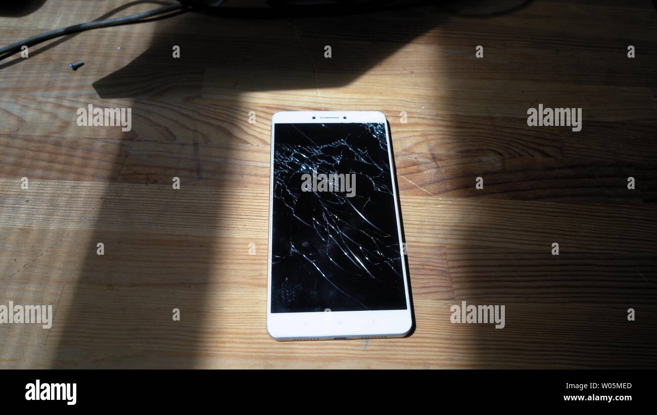 Xiaomi MI Max smartphone with broken screen matrix lies on wooden table ...