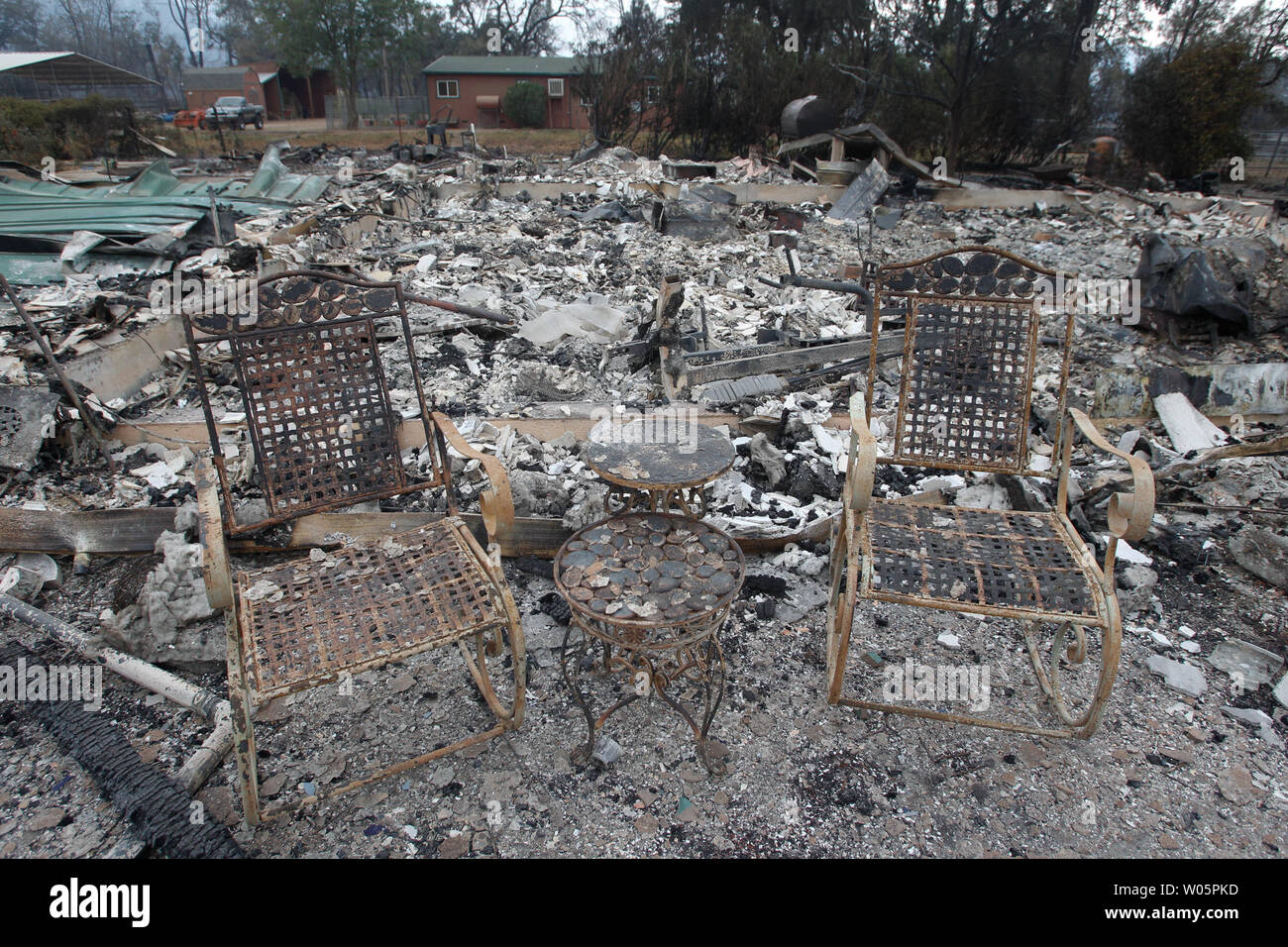 Two chairs sit in front of the burned remains of a house destroyed by ...