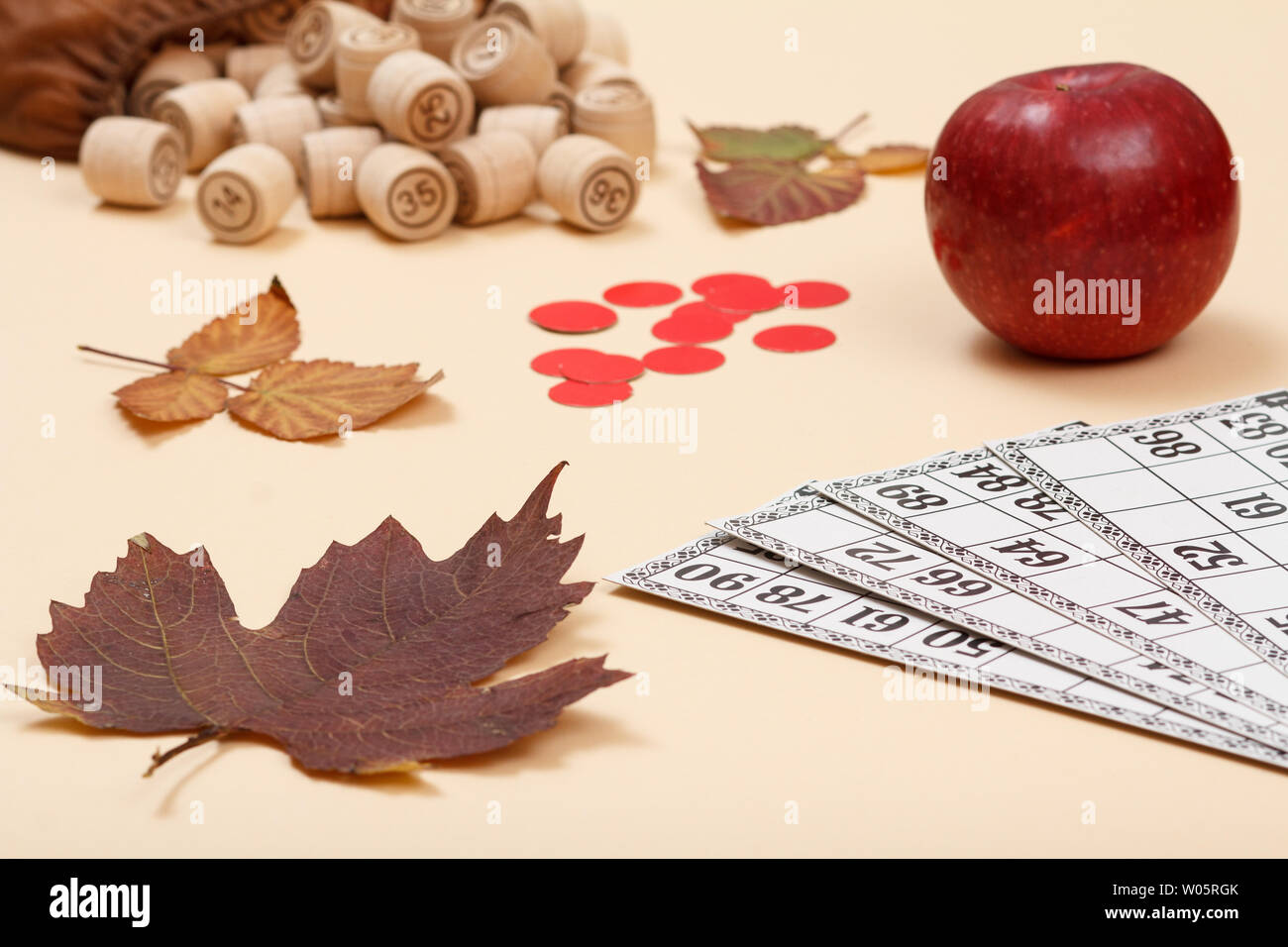 Wooden lotto barrels with open bag, dry autumn leaf, red apple and game ...