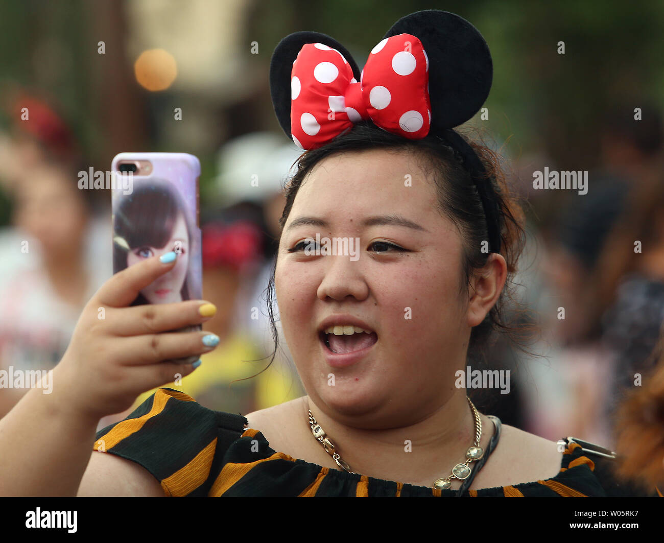 A Chinese woman wearing Minnie Mouse 'ears' takes a selfie in Shanghai ...