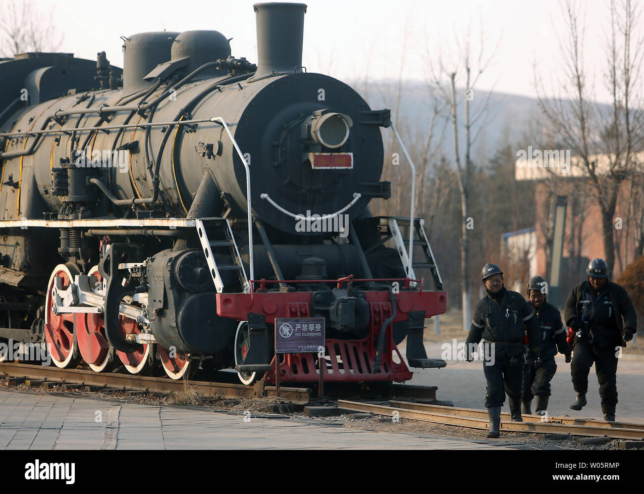 Chinese coal miners walk past an old, coal-powered steam locomotive as ...