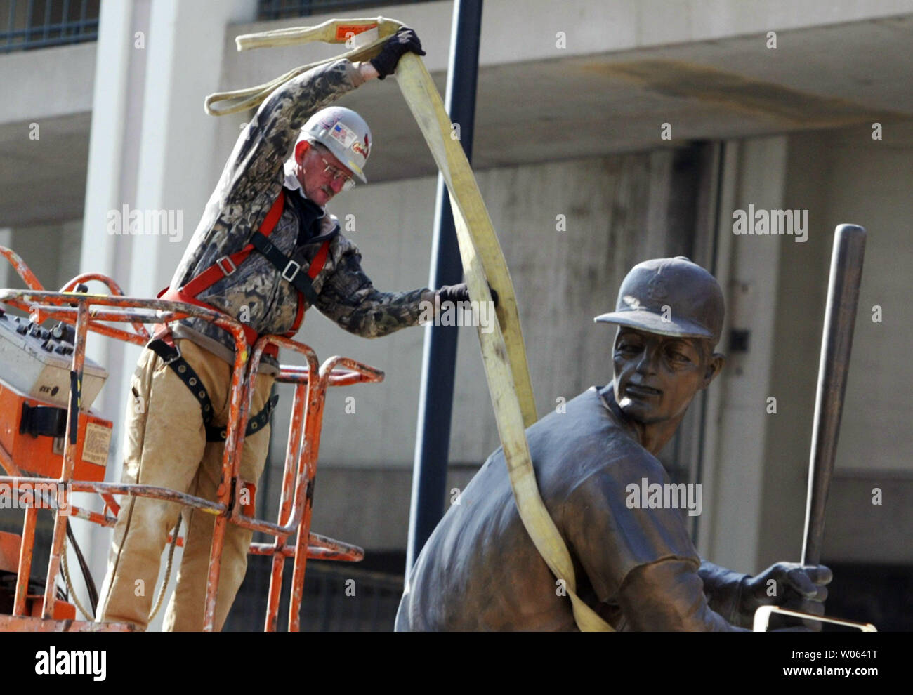 A construction worker holds a harness around the Stan Musial statue as ...