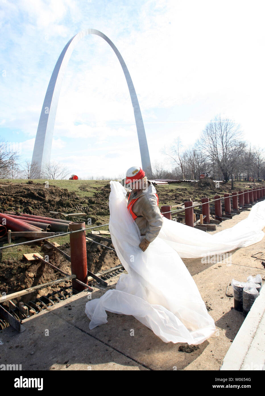 Construction workers cover newly installed steel posts on the grounds ...