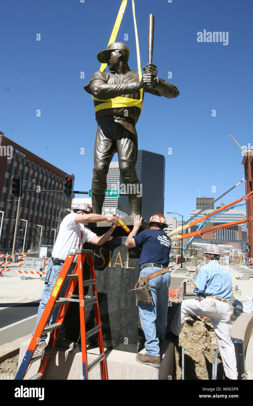 Workers apply epoxy to the base of the Stan Musial statue as its ...