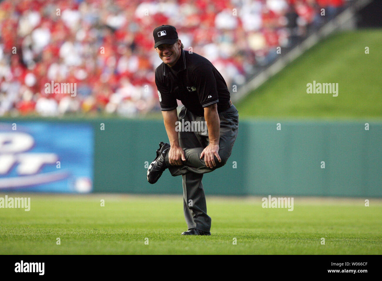First base umpire Jim Wolf has fun stretching between innings during a ...
