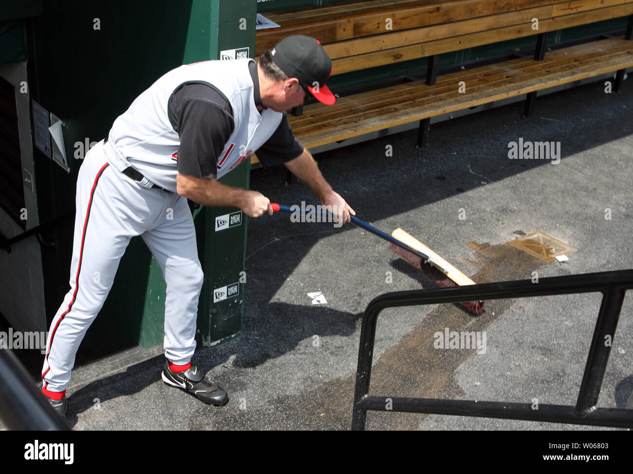 Cincinnati Reds manager Jerry Narron uses a broom to clear away water ...
