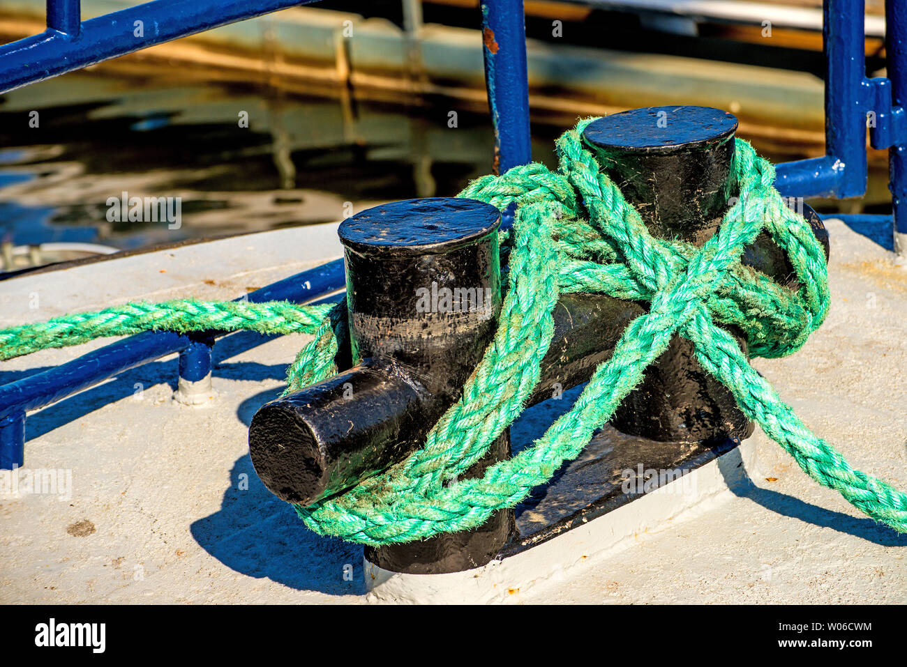 Mooring line of a trawler at blue cleats Stock Photo - Alamy
