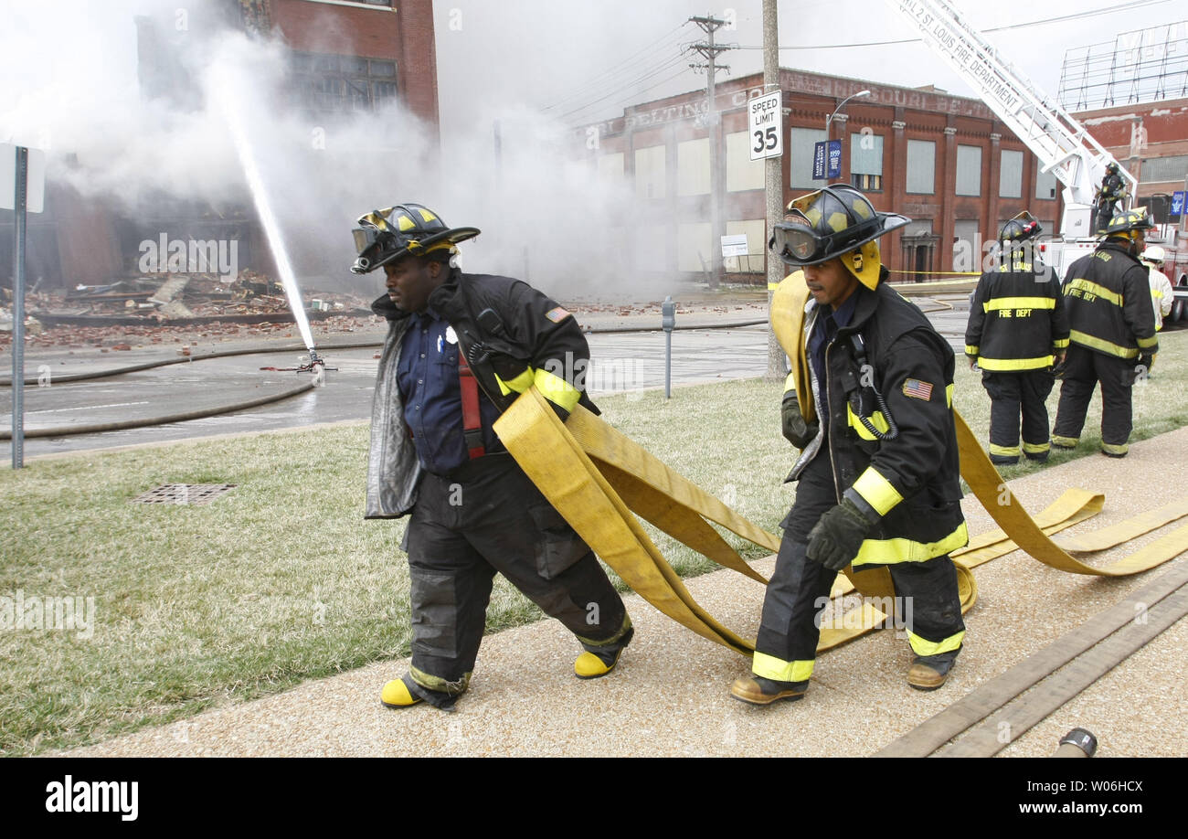 St. Louis firefighters drag hose up the street as fire destroys a ...