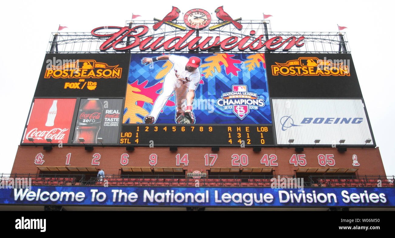 A lone stadium worker places chairs in place below the scoreboard at ...