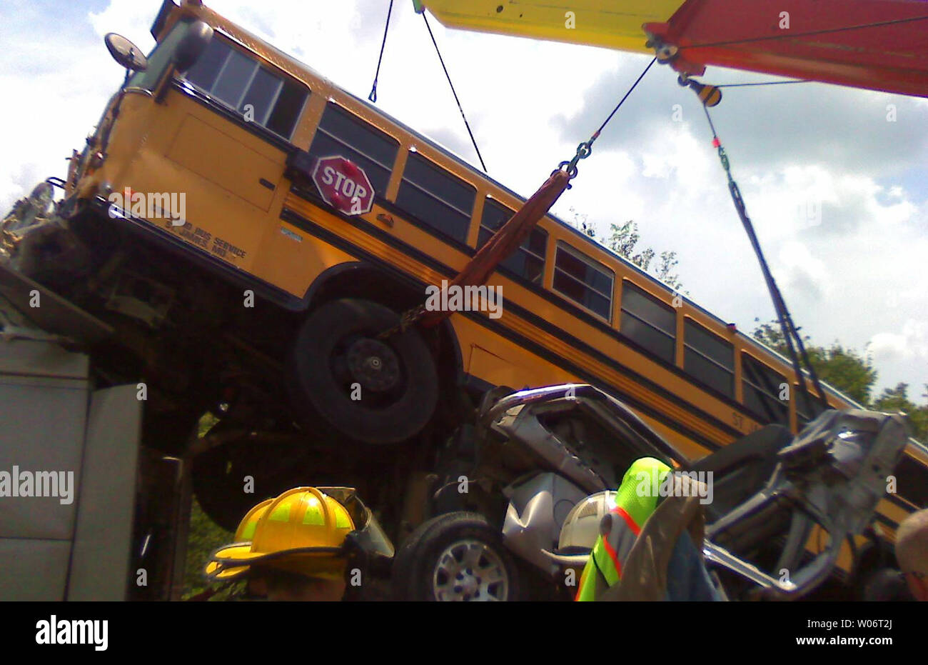 A crane works to lift a school bus off of the back of a tractor trailer ...