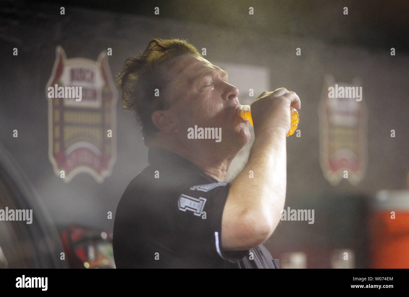 Umpire Gerry Davis takes advantage a fan spray and a cool drink between ...