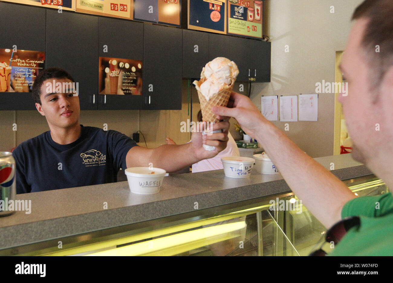 Scooper Bryce Jackson hands over a vanilla ice cream cone to a customer ...