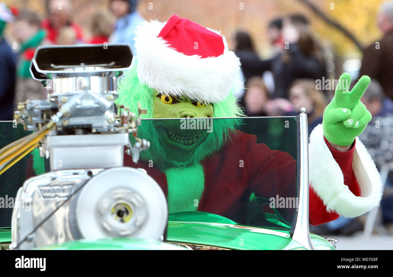 A grinch santa waves to the crowd while driving a hot rod during the ...