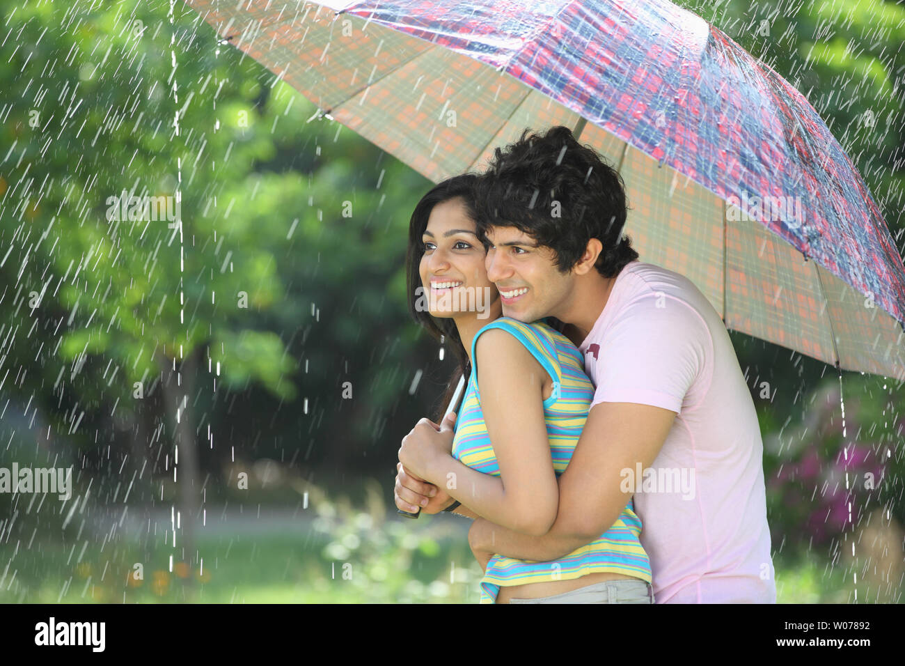 Couple romancing under an umbrella in rain Stock Photo - Alamy