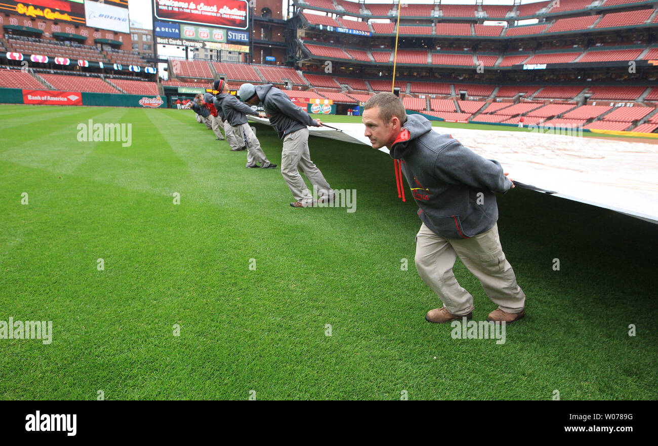 Busch Stadium groundskeepers pull the tarp off the infield to drain the ...